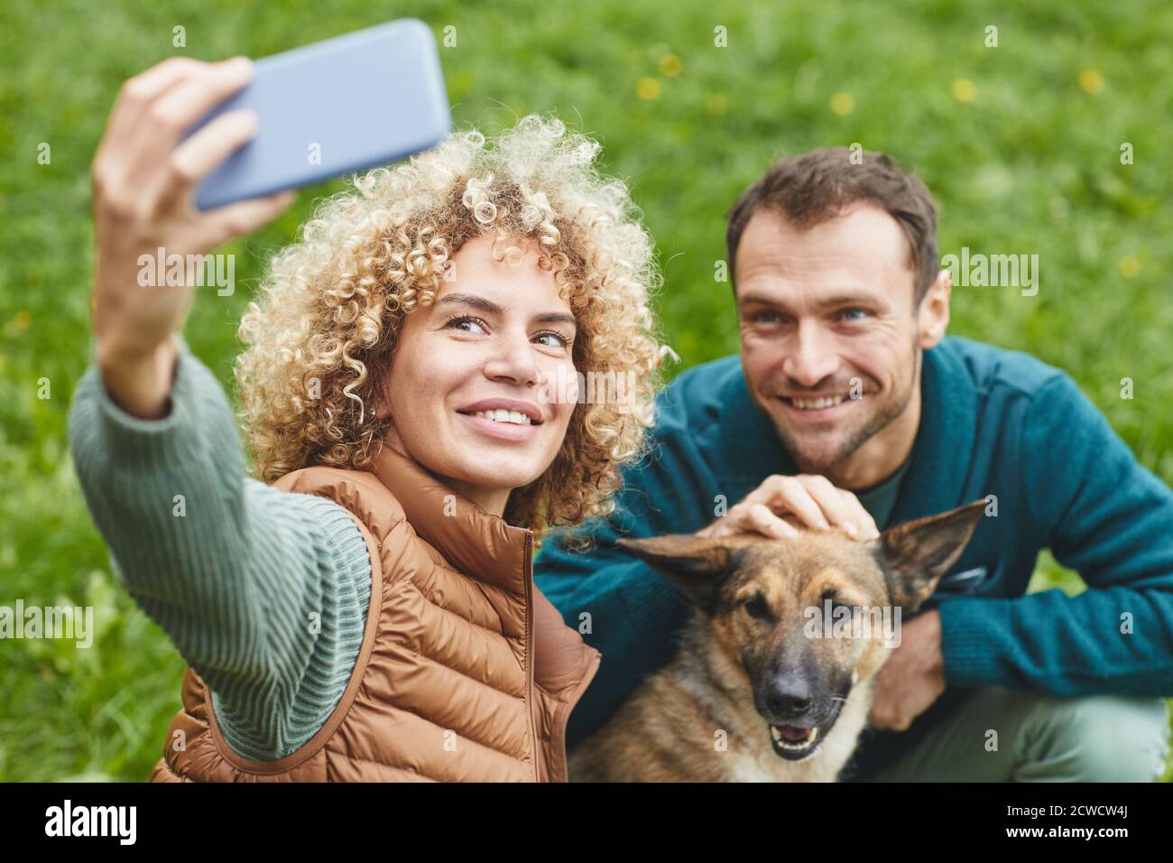 Young woman making selfie portrait on her mobile phone with dog and her ...