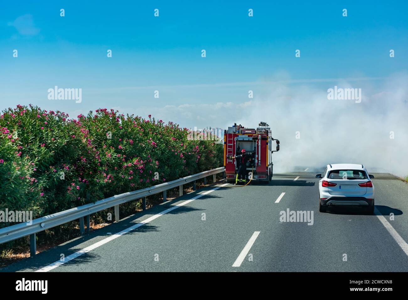 Fire truck putting out a fire in the bushes of the median of the ...