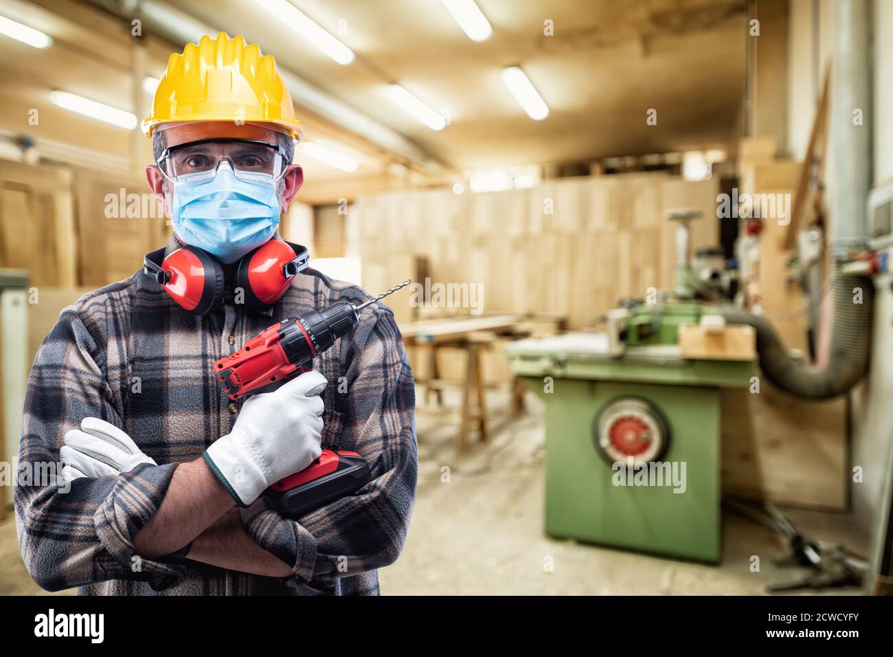 Carpenter worker in the carpentry workshop, wears helmet, goggles ...
