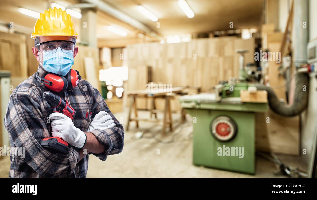 Carpenter worker in the carpentry workshop, wears helmet, goggles ...