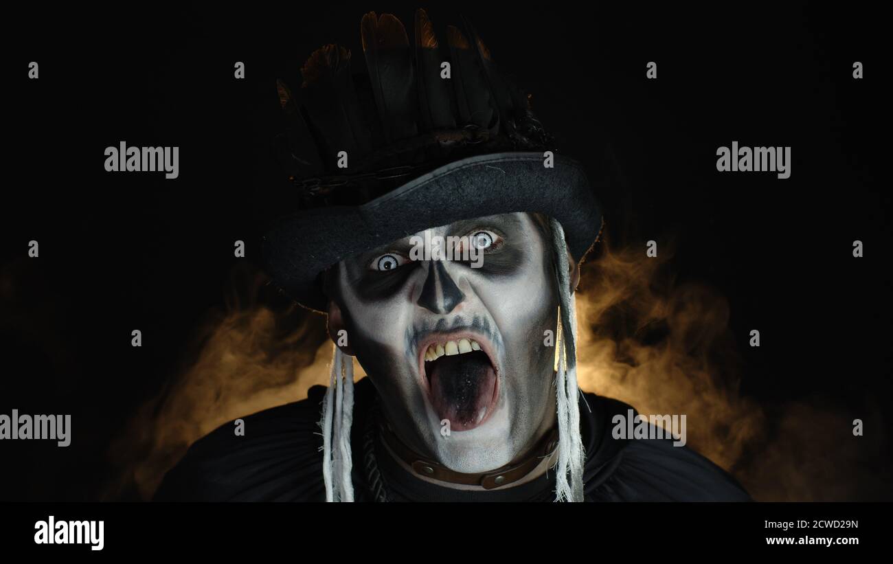 Creepy, crazy man with skeleton makeup in top-hat. Guy making angry ...