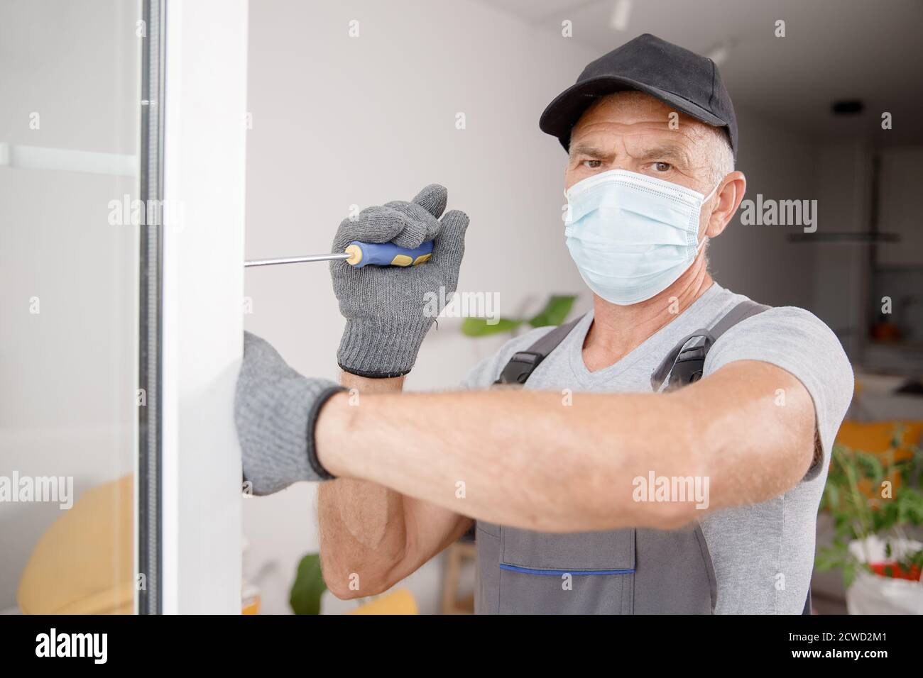 Worker man installs plastic windows and doors with double-glazed white ...