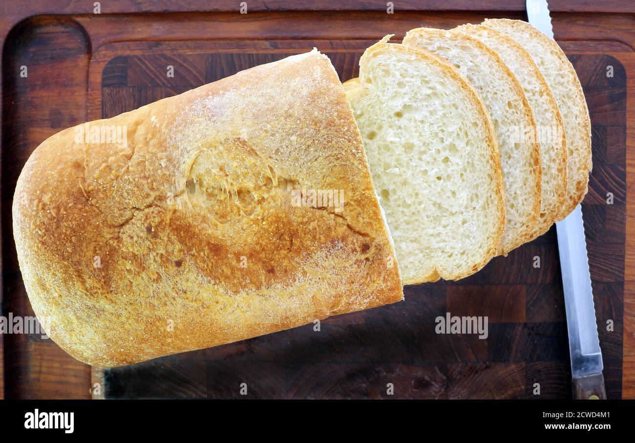 Overhead angle, Loaf of fresh home made bread, sliced, on dark cutting ...