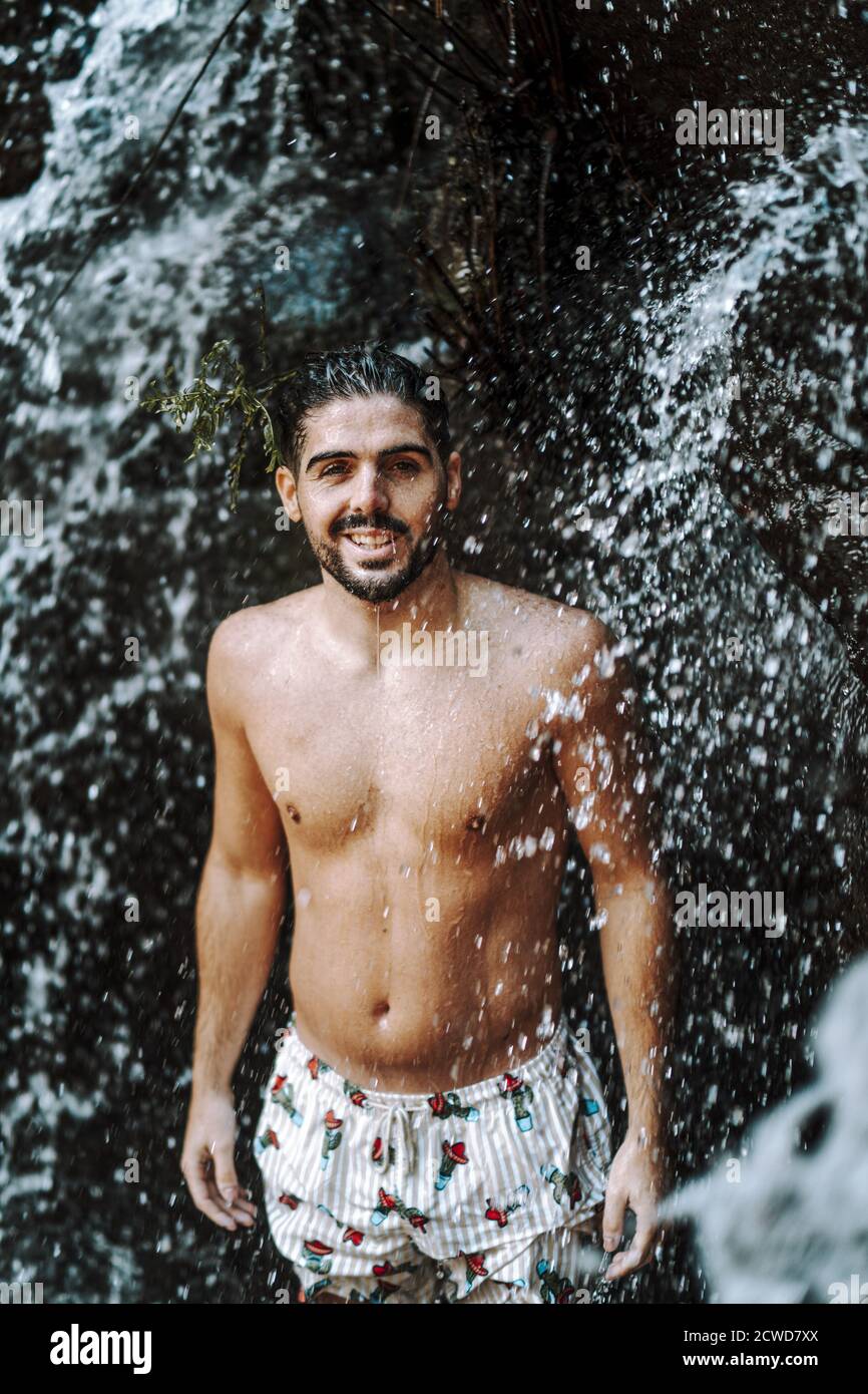 Young Caucasian athletic male at a waterfall near rocks enjoying the ...
