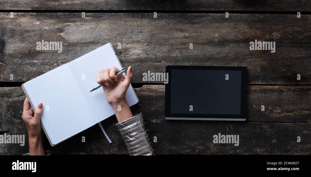 Top view of a woman about to make notes in a blank open notepad next to ...