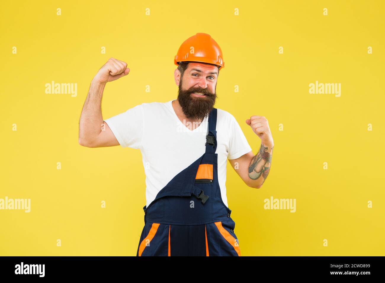 Power building. Strong construction man flex arms yellow background ...