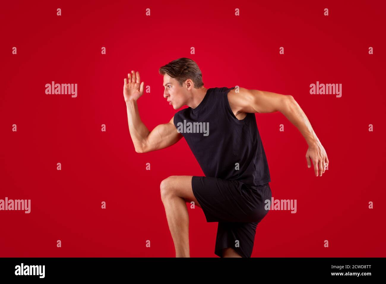 Portrait of focused young man running fast on red studio background ...