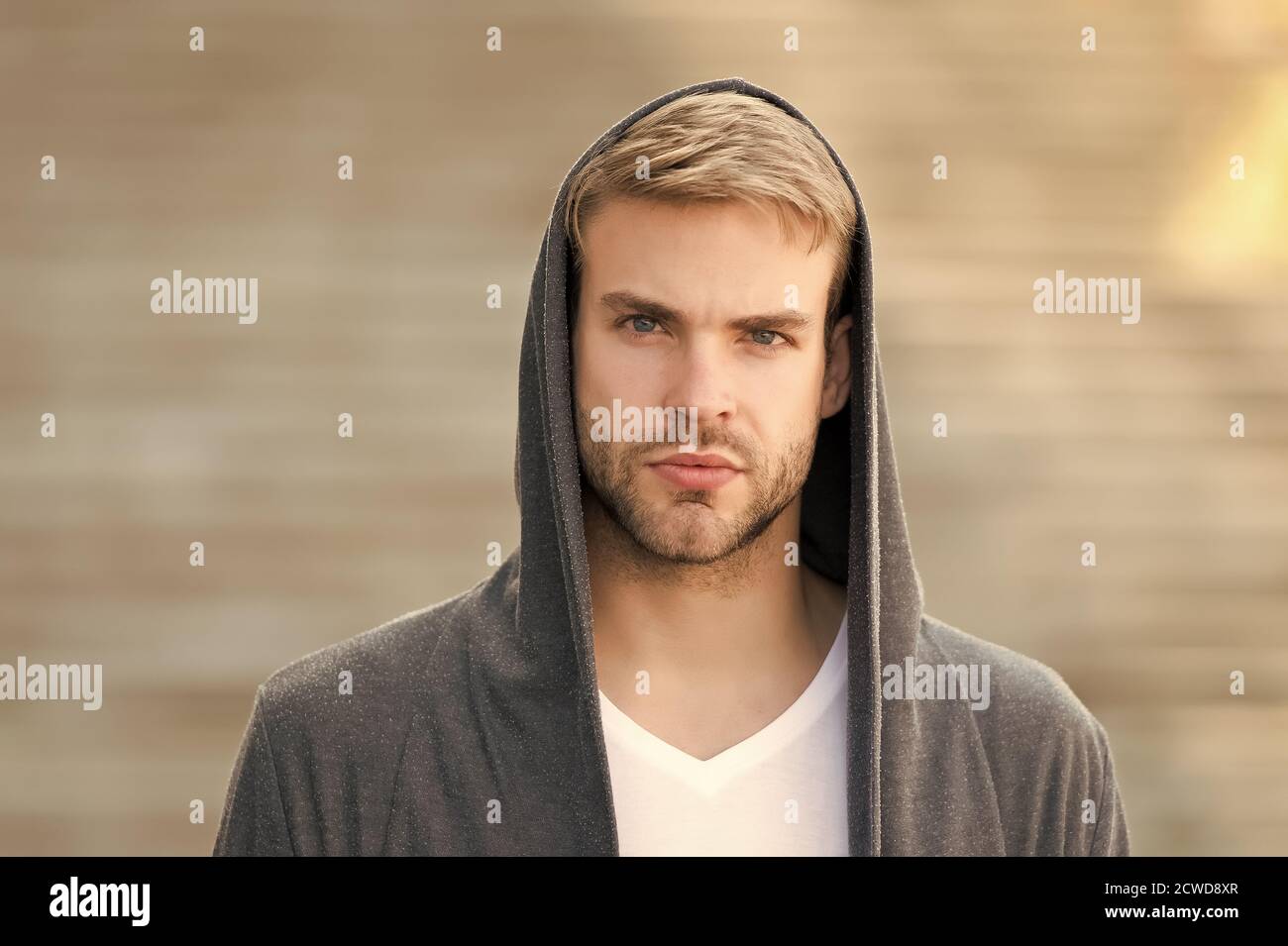 Popular street style. Handsome man with hood standing urban background ...
