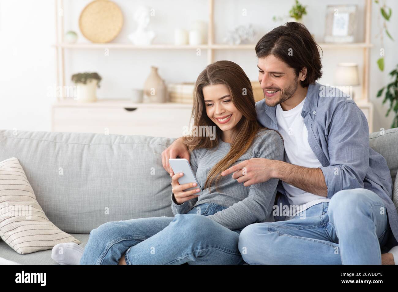 Happy married couple watching photos on smartphone Stock Photo - Alamy