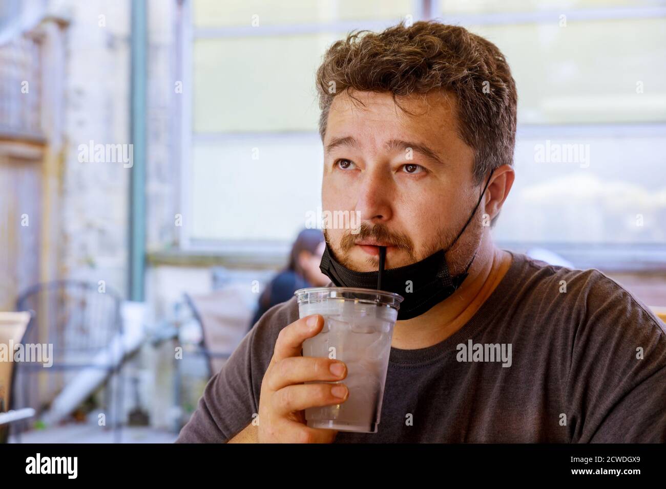 Man with mask drinking water in restaurant on the bar counter ...