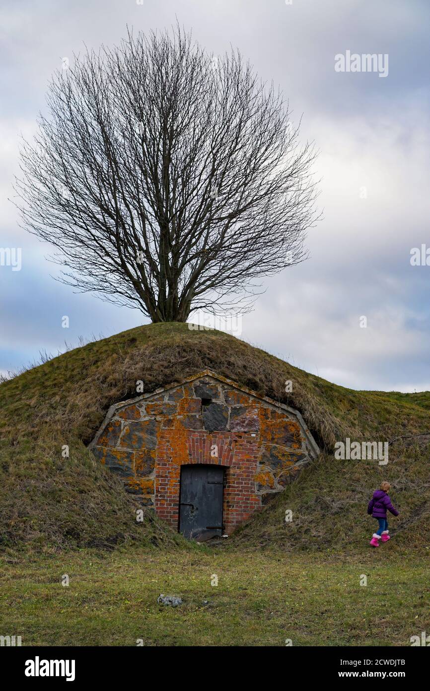 Structure built into the side of a hill with tree and child climbing ...