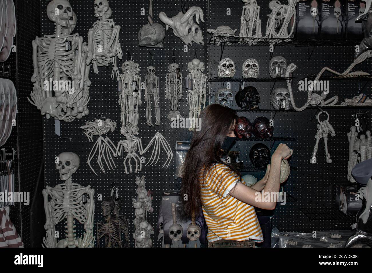 Woman in pandemic coronavirus COVID-19 mask shops for Halloween skull ...