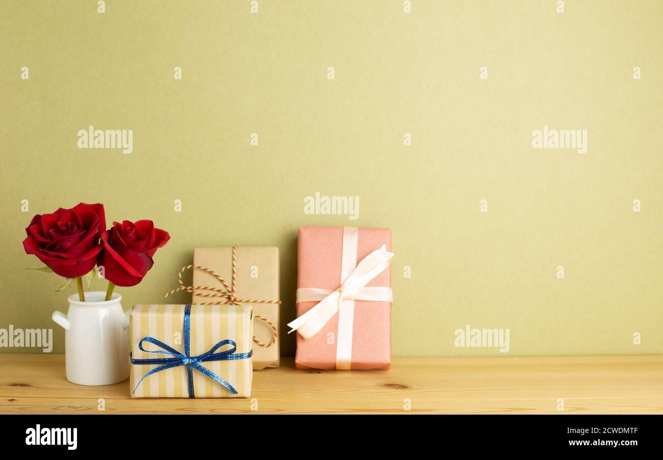 Gift boxes with red rose flowers on wooden table with khaki background ...