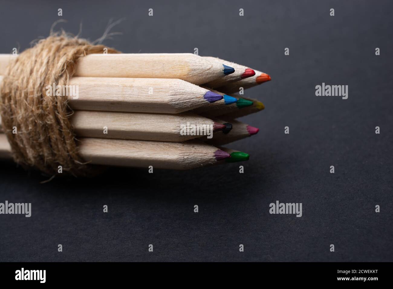 Bundle of colored pencils wrapped with string on black Stock Photo - Alamy