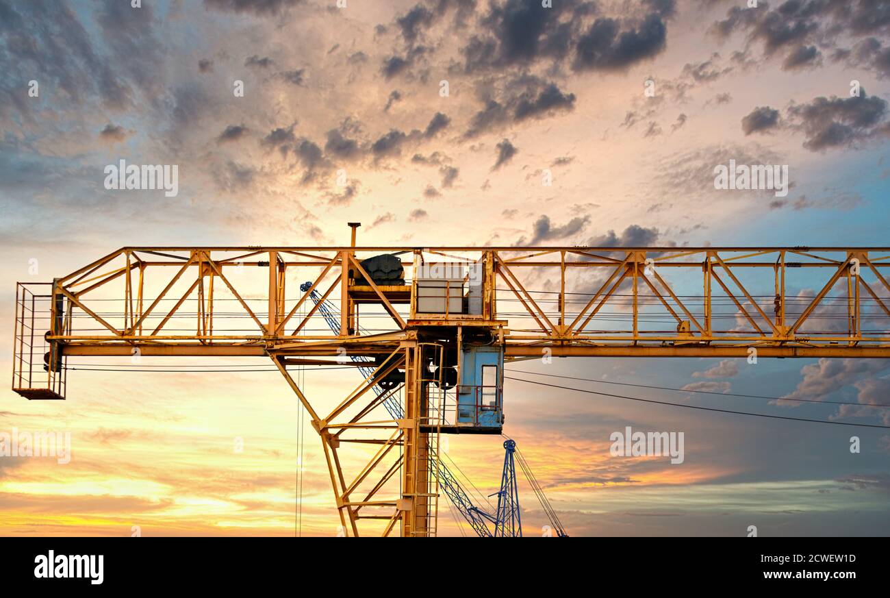 Industrial construction cranes and building silhouettes over sun at ...