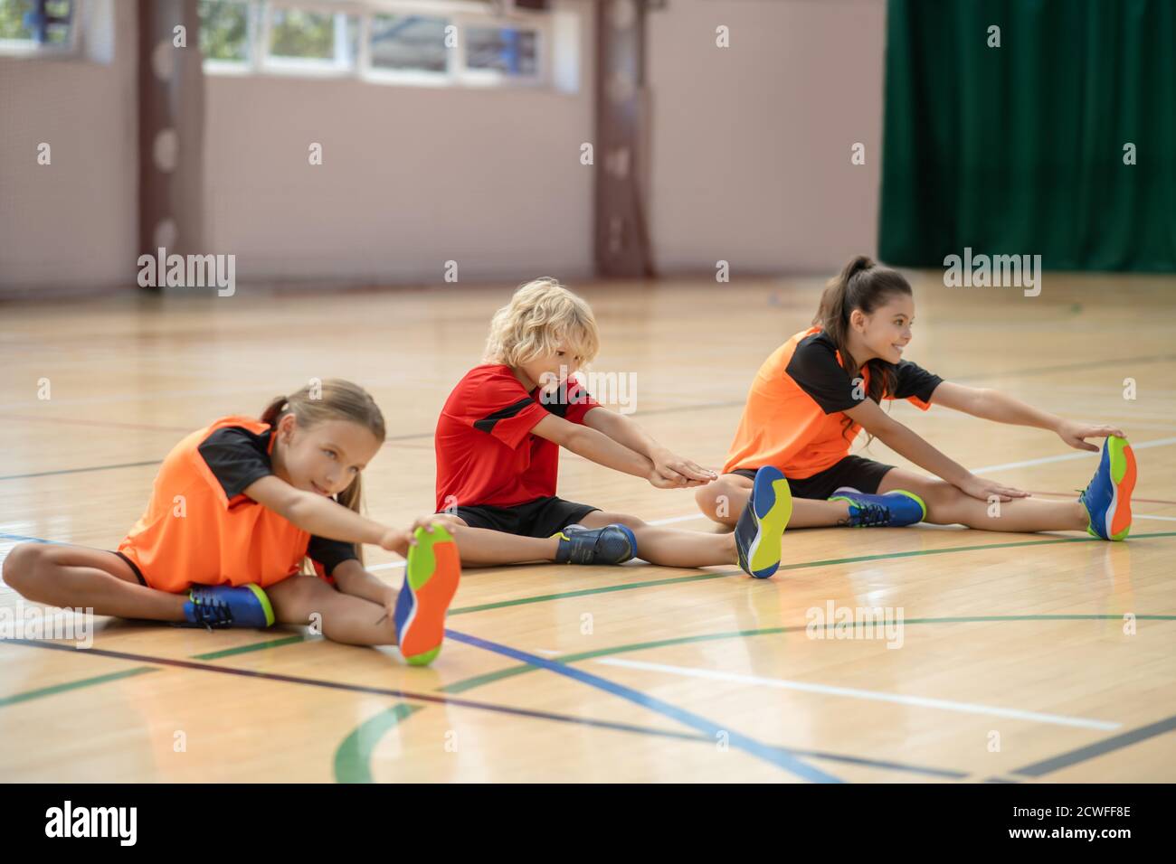 Three kids in bright sportswear exercising in the gym Stock Photo - Alamy