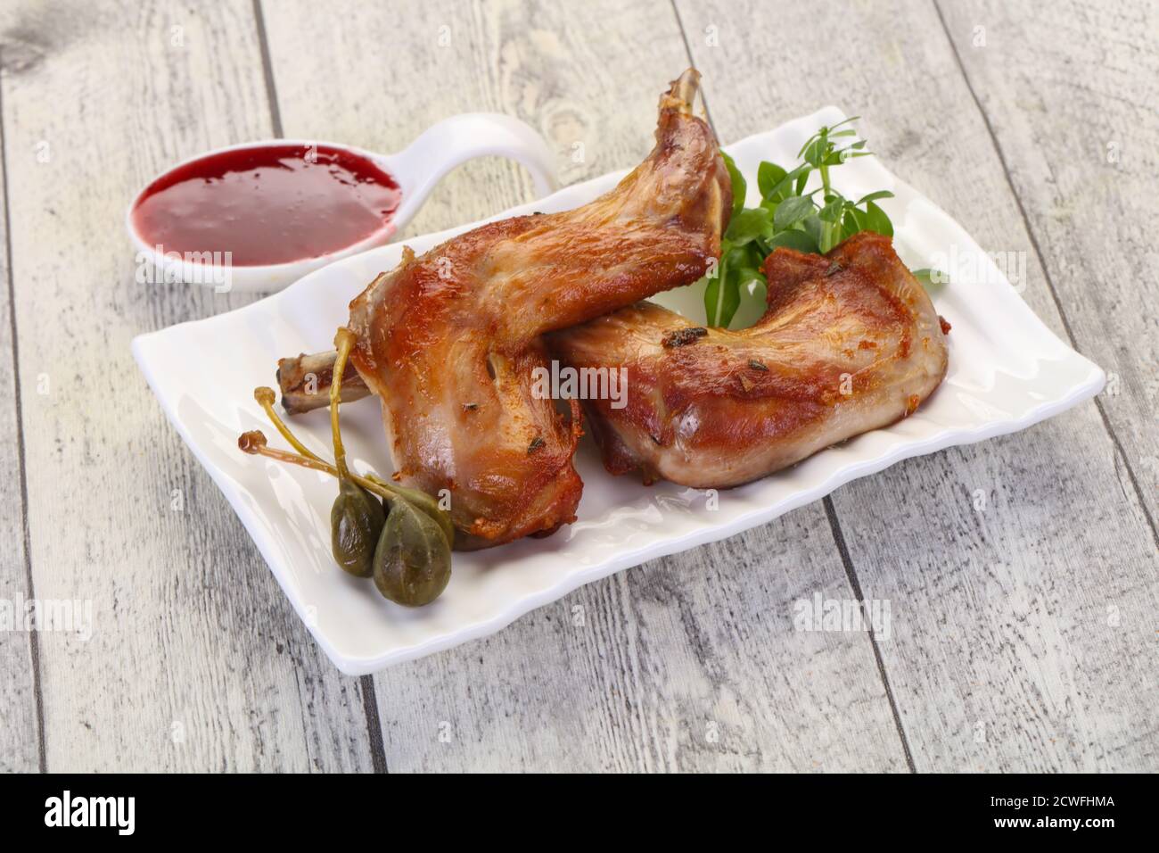 Roasted rabbit legs with cowberry sauce Stock Photo - Alamy