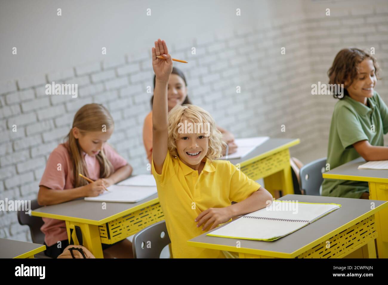 Boy raising hand in classroom hi-res stock photography and images - Alamy