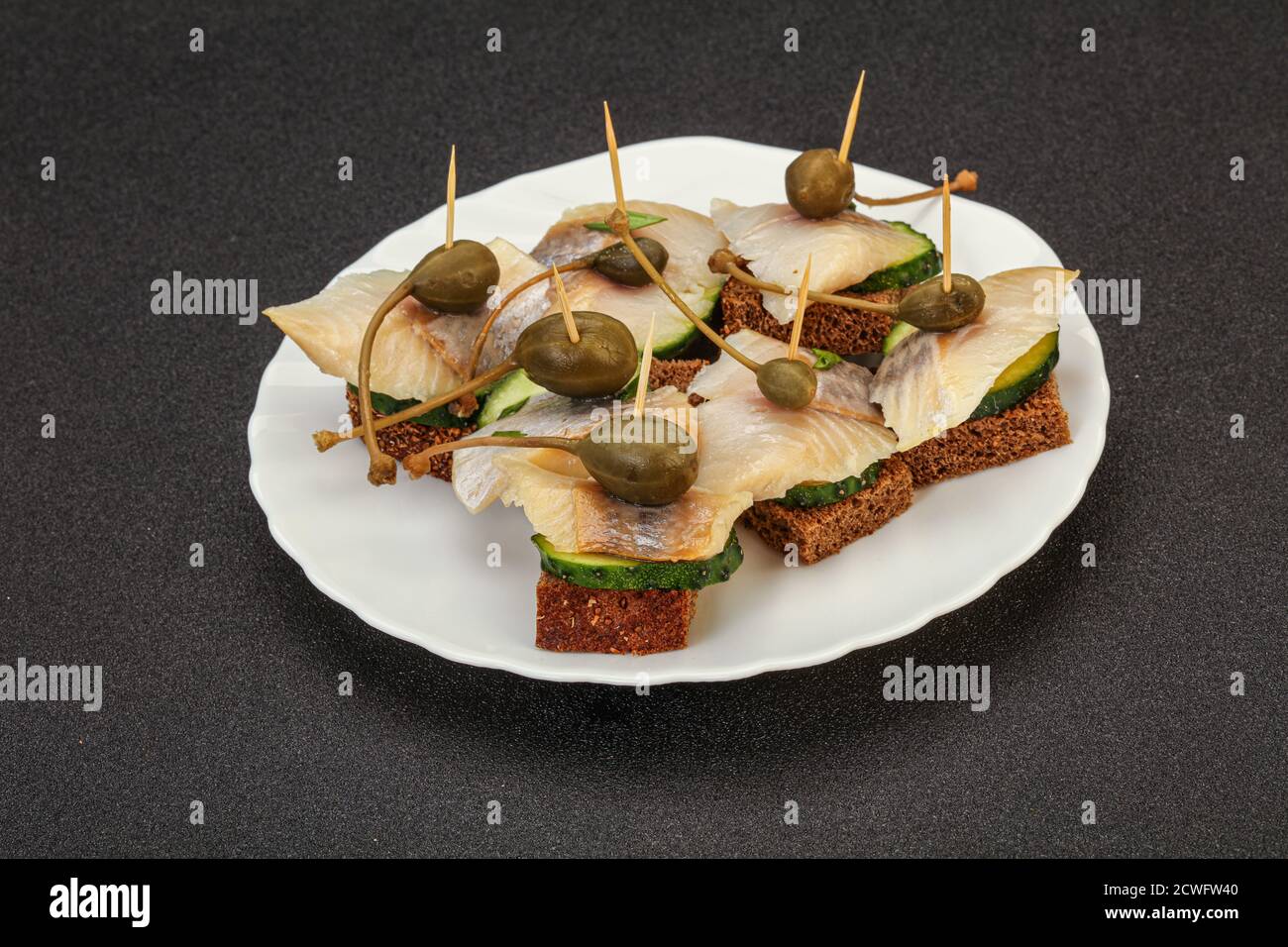 Herring fillet canape snack with caperberry and cucumber Stock Photo ...