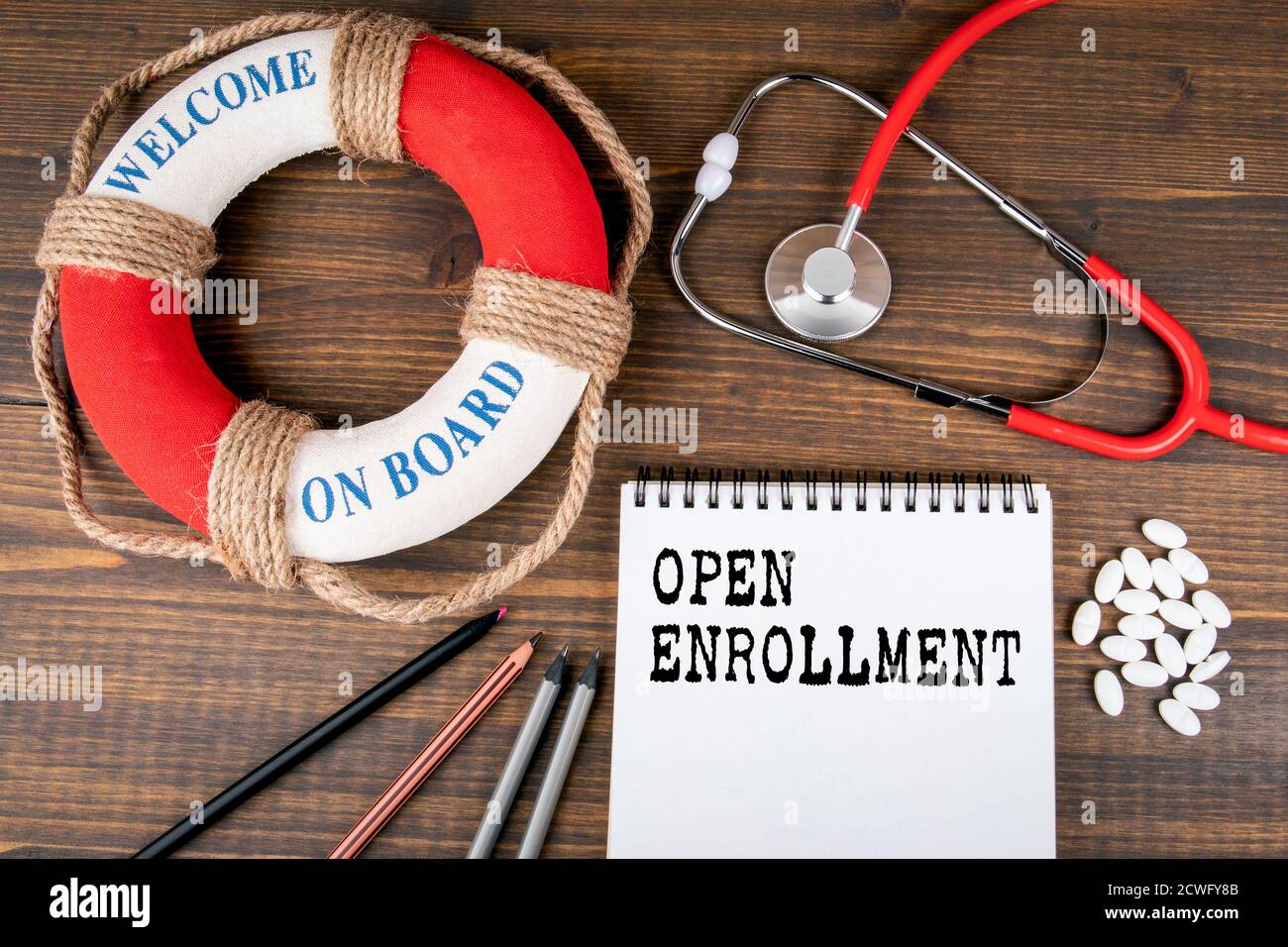OPEN ENROLLMENT. Lifebuoy with text and doctor's stethoscope on wooden ...
