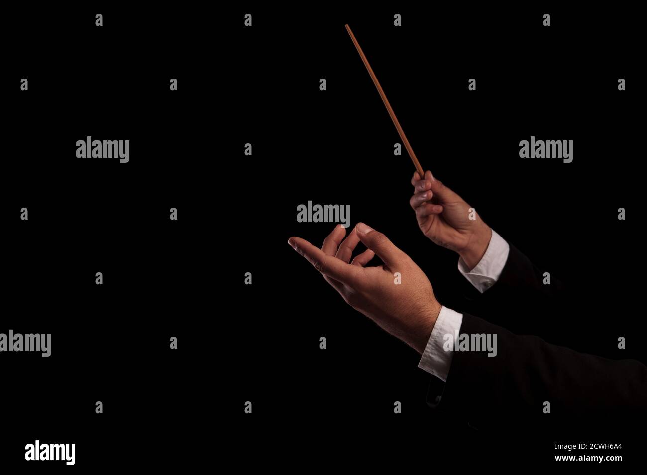 conductor's hands conducting an orchestra on black studio background ...