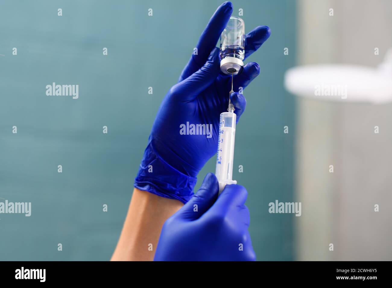 Female Hands In Blue Rubber Gloves Hold Medical Syringe And Fill Needle