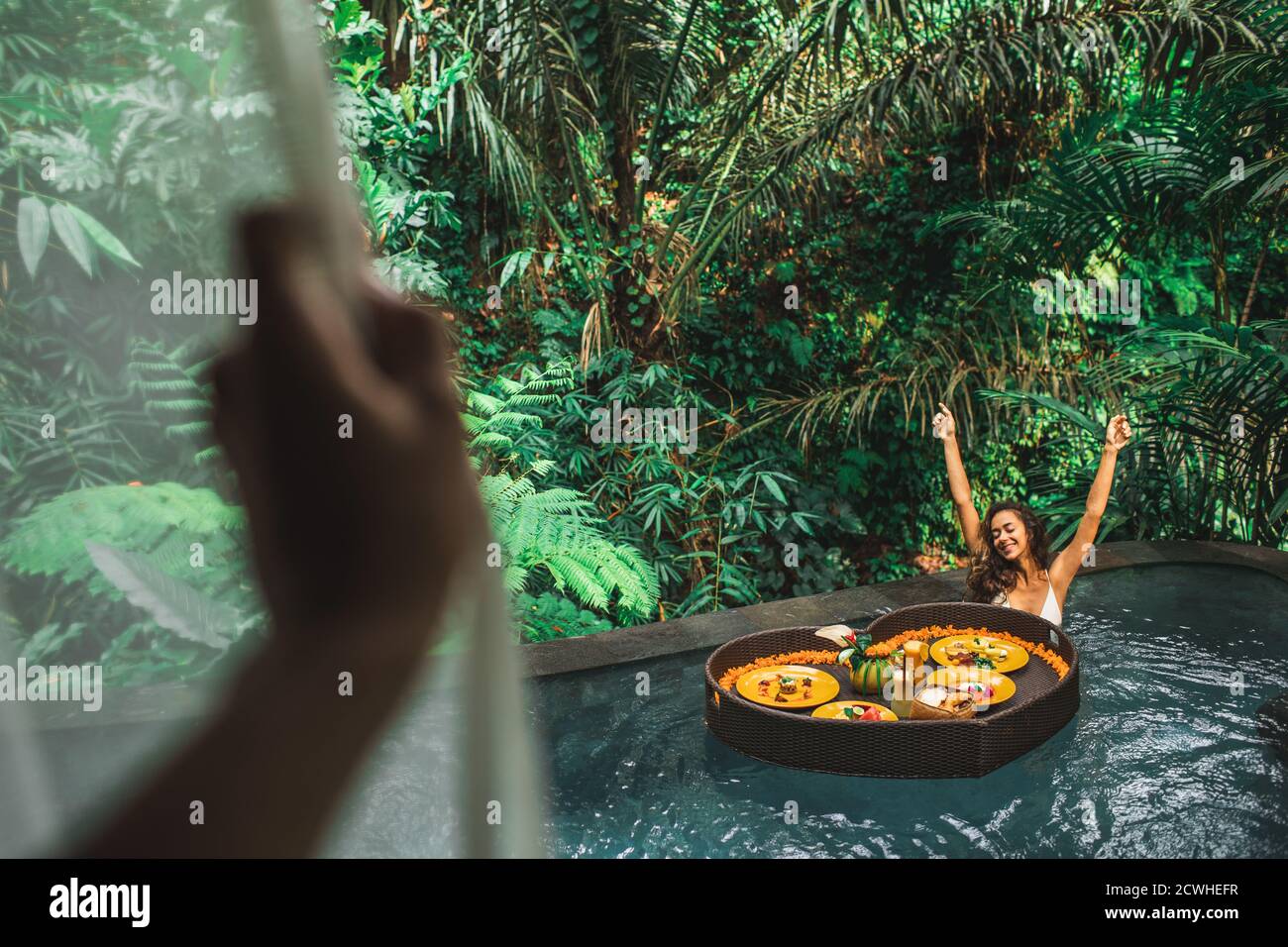 Girl relaxing and eating floating breakfast in jungle pool on luxury ...