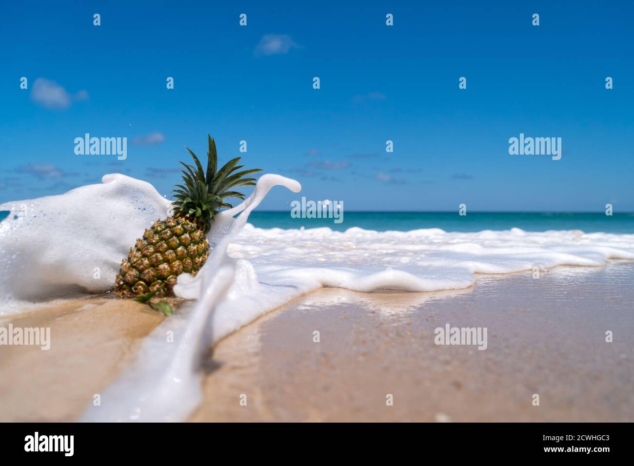 Pineapple on sand with sea water splash on blue sky summer concept ...