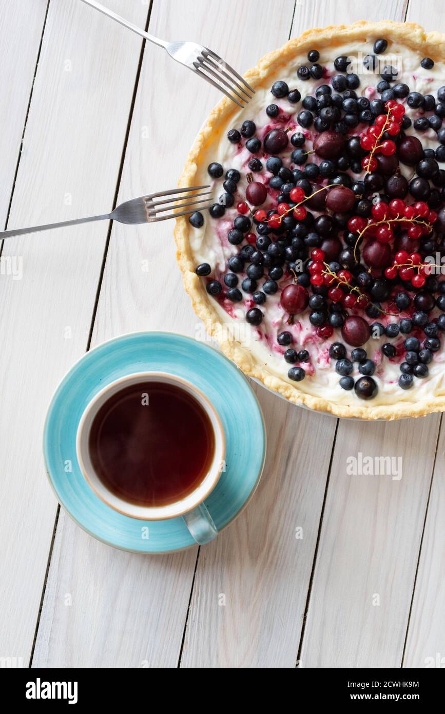 Blueberry open pie with cup of black tea on bright painted wood ...