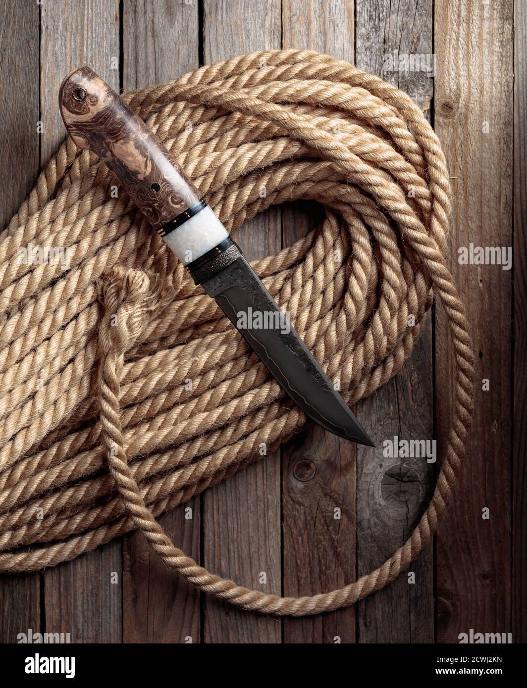 Hunter combat hand made knife and hemp rope on wooden background. The ...