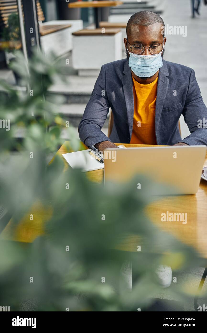 Attentive dark-skinned man staring at screen of his computer Stock ...