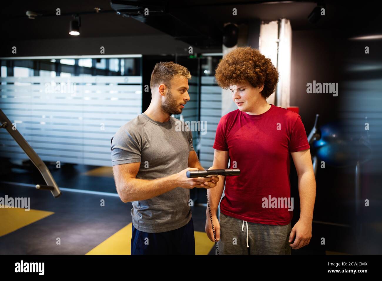 Overweight young man exercising gym with personal trainer Stock Photo ...