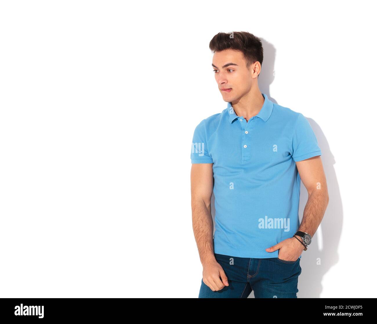 anxious man biting his lip and looks to a side , standing against white ...