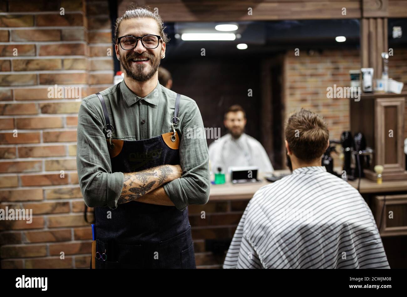 Portrait of happy young barber with client at barbershop and smiling ...