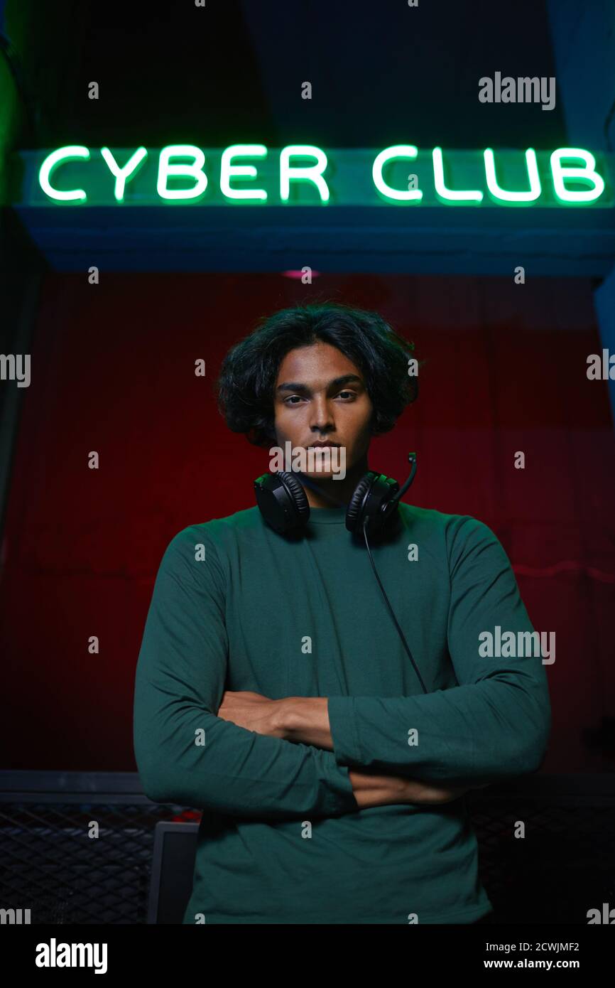 Portrait of serious gamer standing with arms crossed and looking at ...