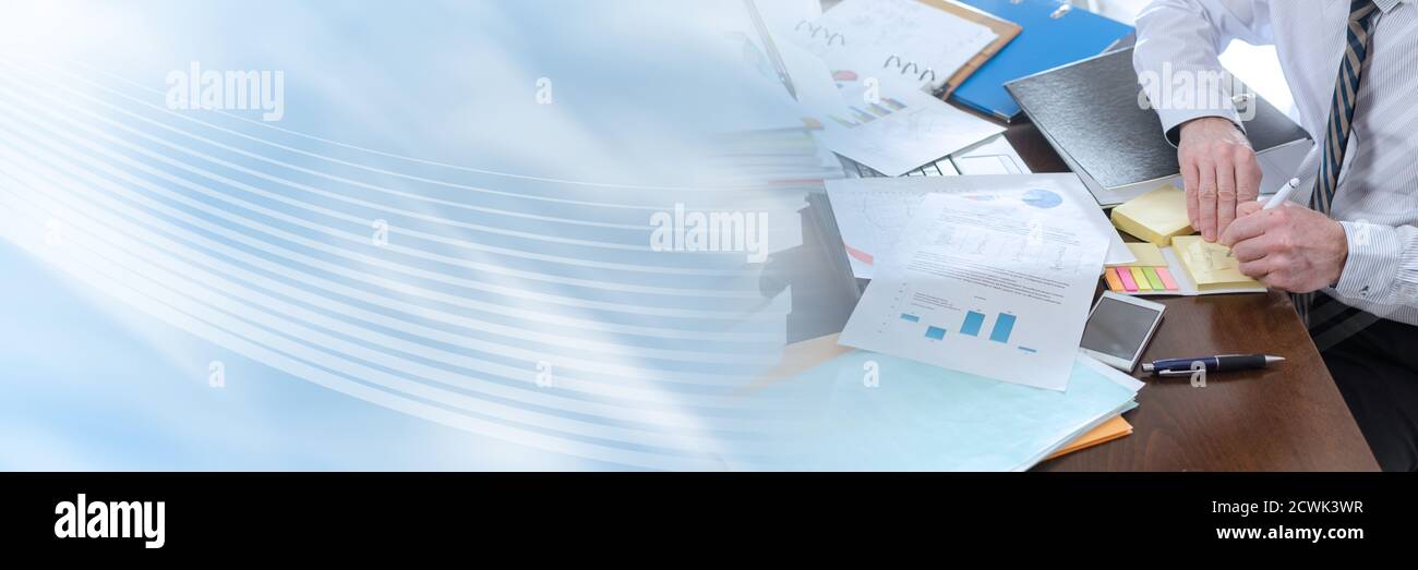 Businessman working at an untidy and cluttered desk; panoramic banner ...