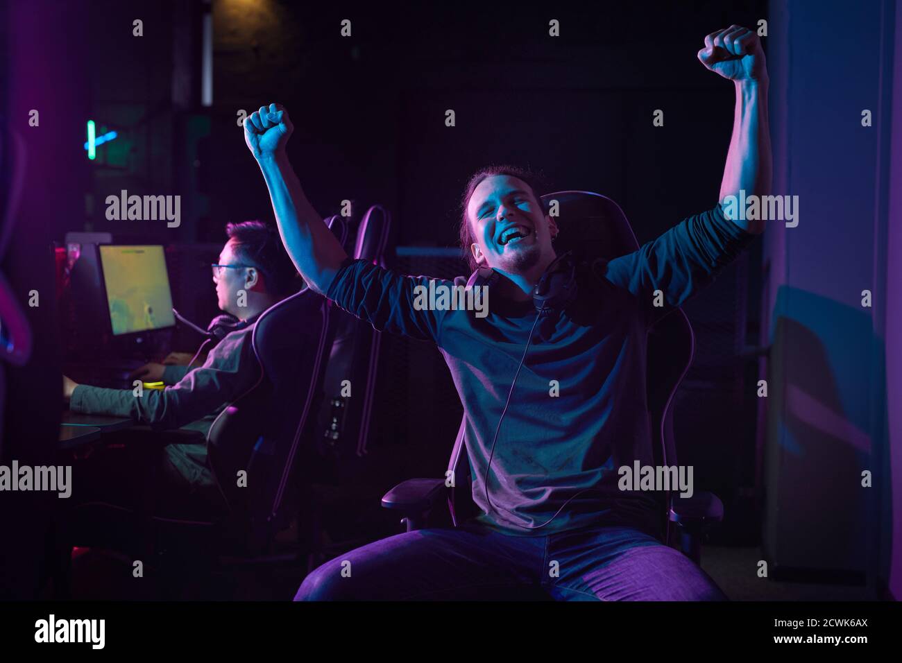 Portrait of an excited gamer sitting on a chair and enjoying his ...