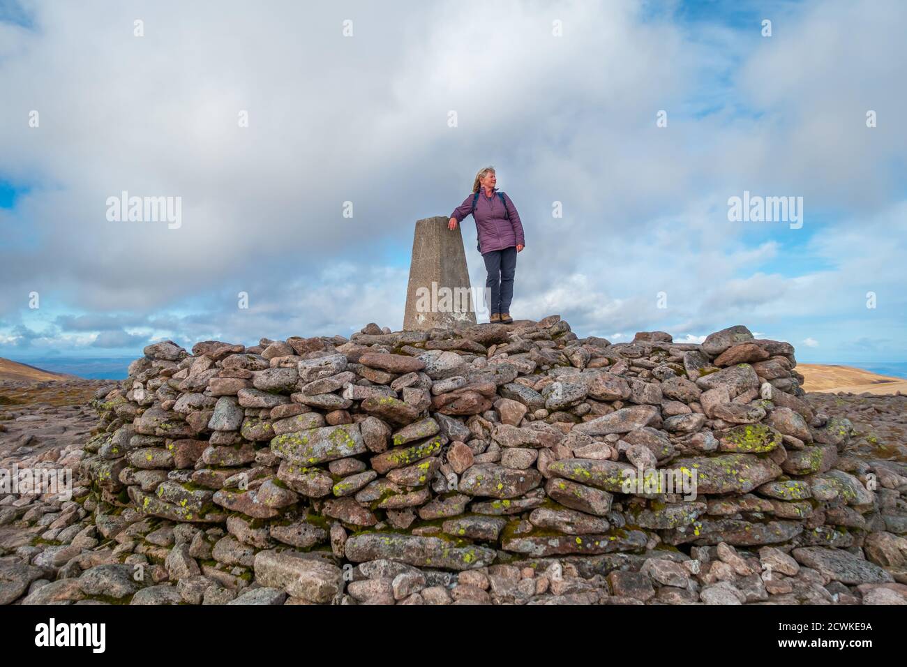 Walker at the trig point at the summit of the mountain Ben Macdui, the ...