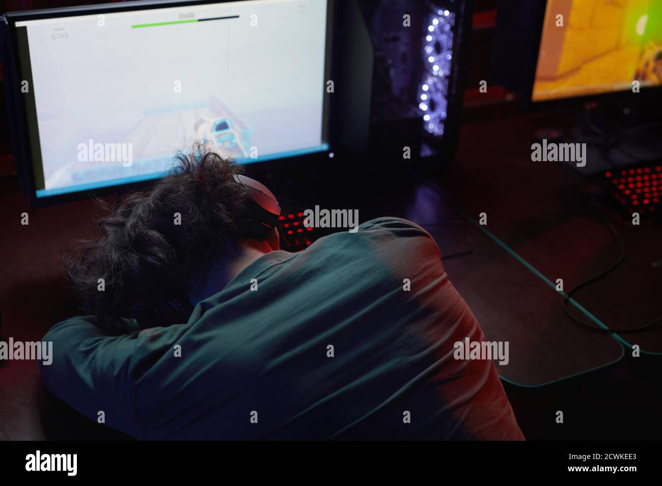 Rear view of exhausted computer programmer sleeping at his workplace in ...