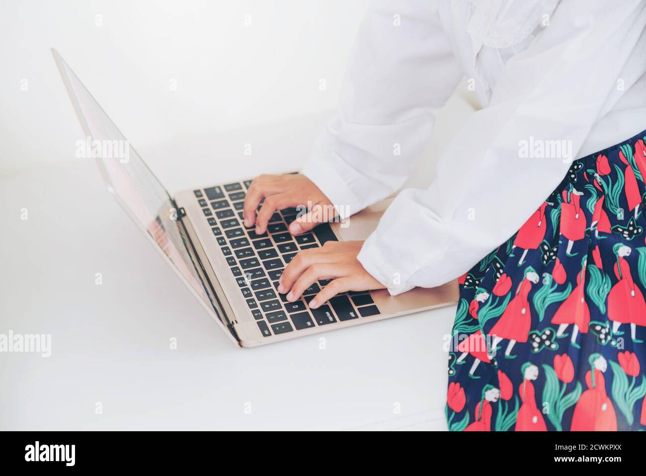 Little kid using laptop computer sitting on white background. Close up ...