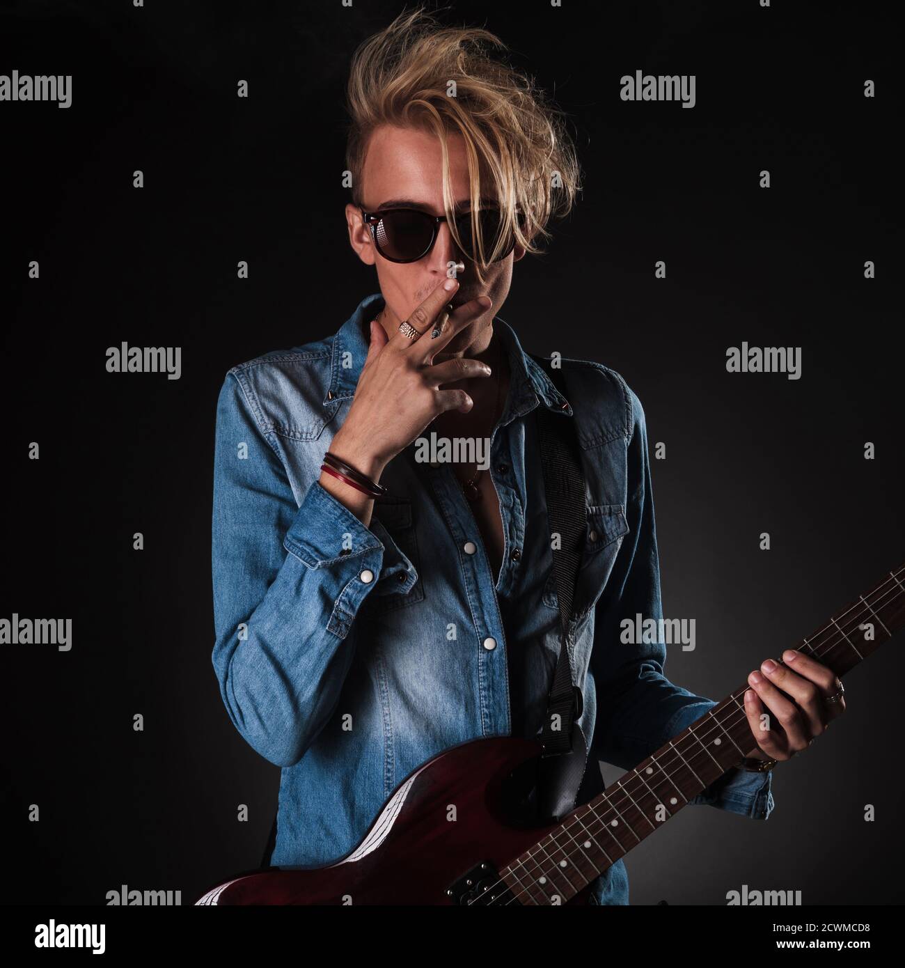 cool guitarist smoking his cigarette in studio and holds electric ...