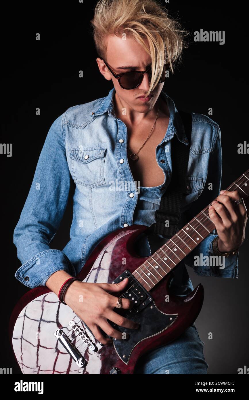 young blonde man playing rock and roll music on his electric guitar ...
