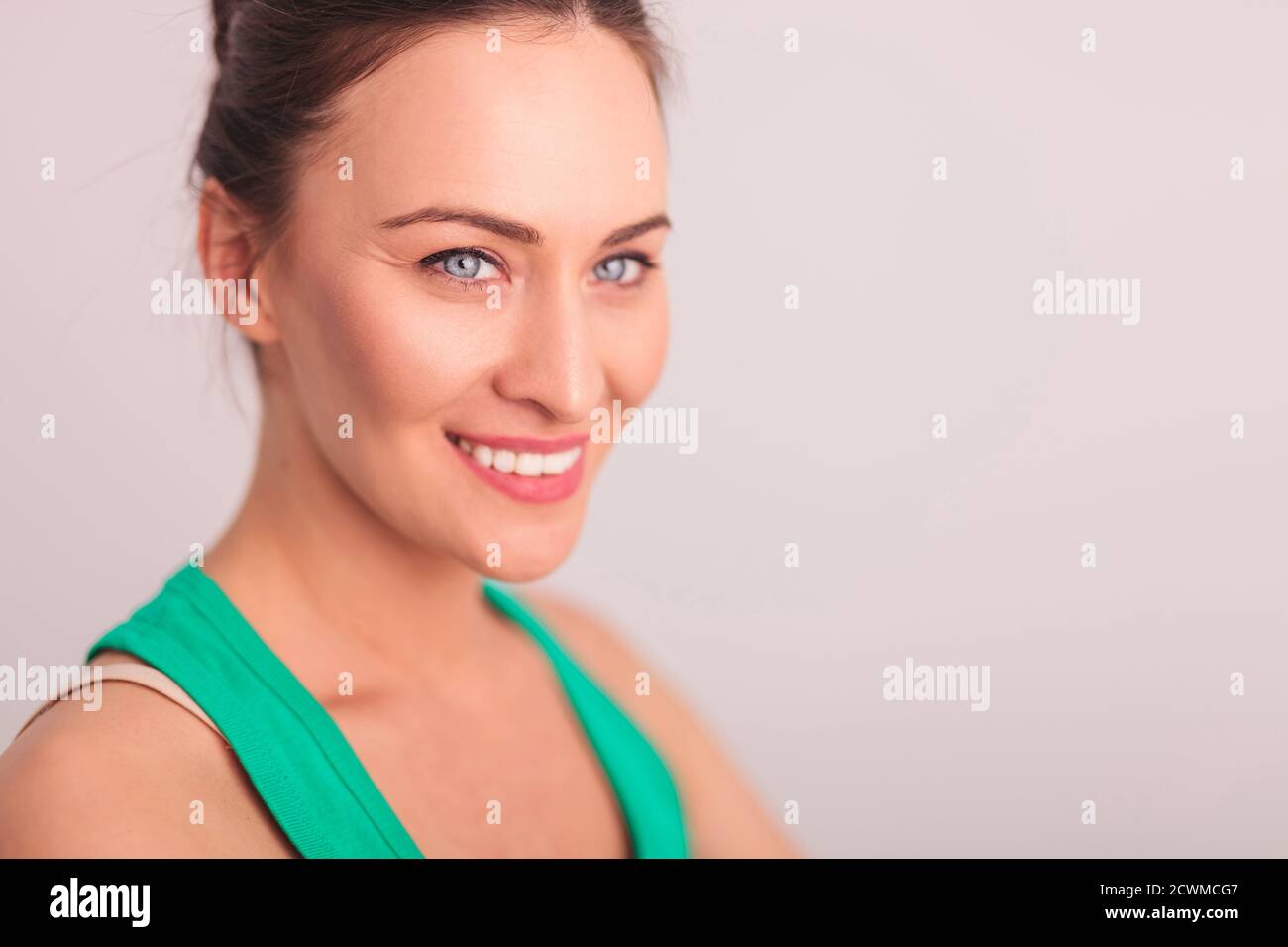 side of a smiling woman's face looking away from the camera in studio ...
