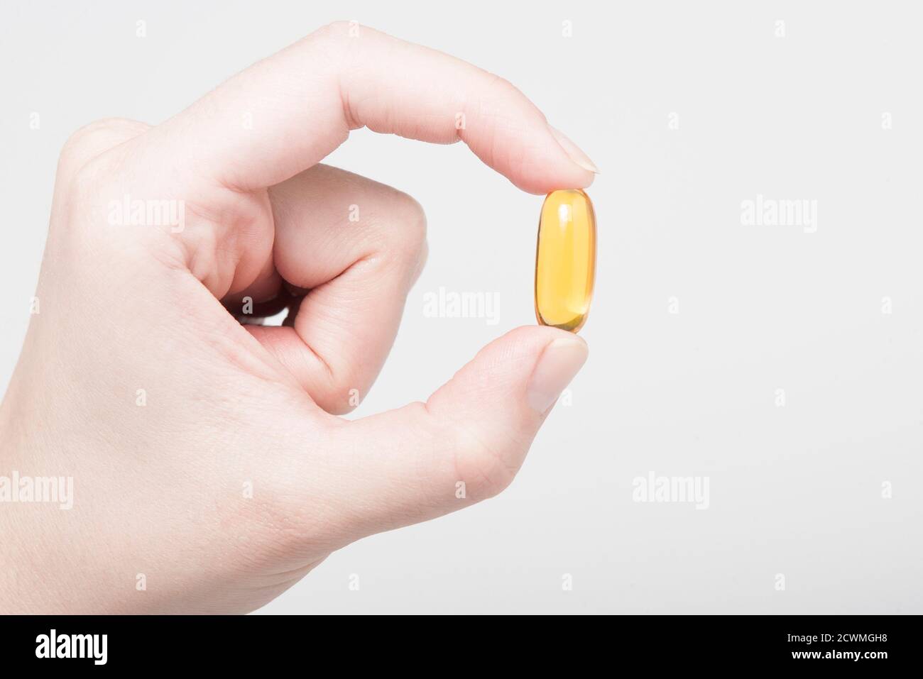 Yellow Omega 3 capsule squeezed in fingers on white background Stock ...