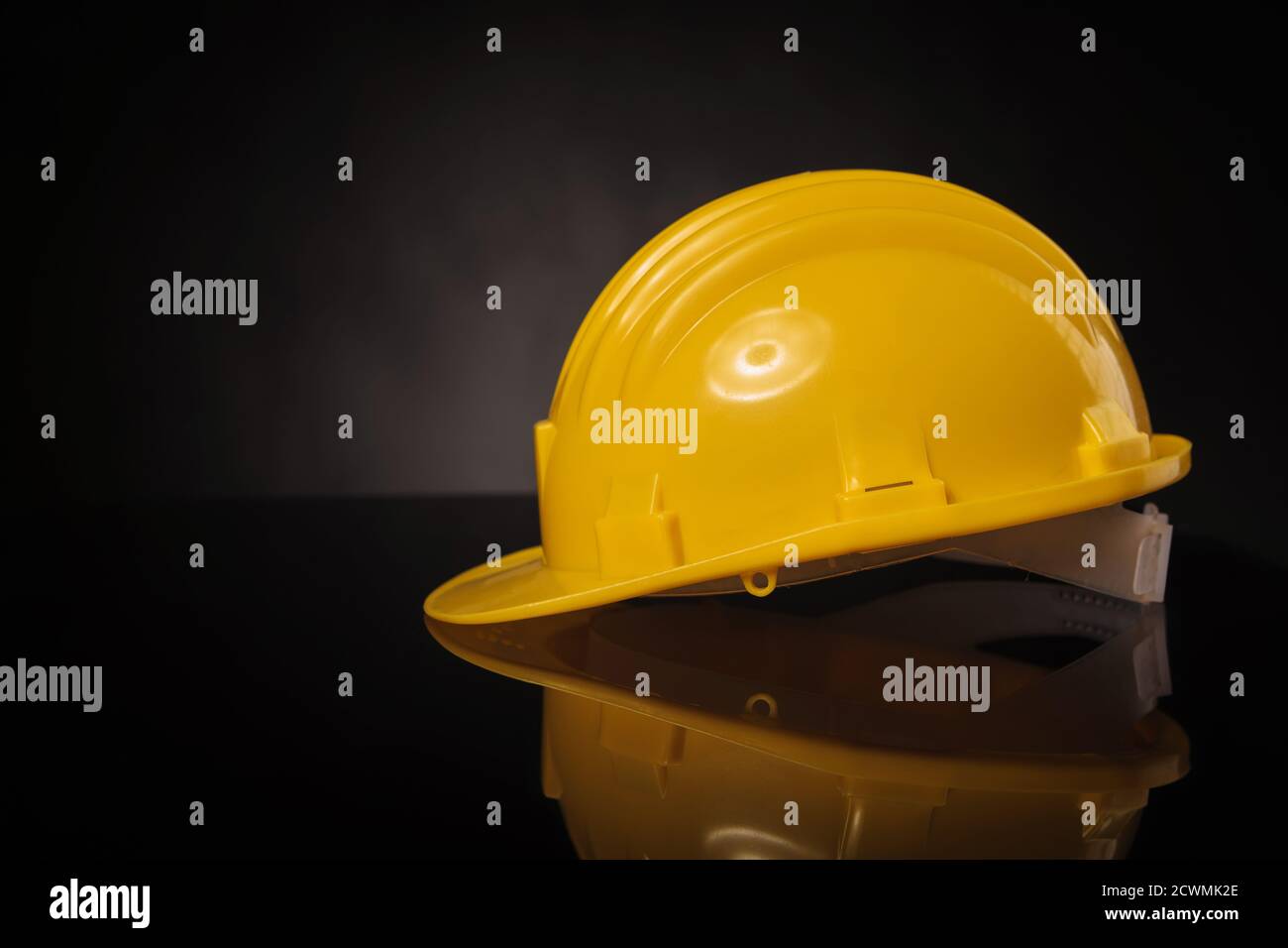 side view of a yellow construction safety helmet on a black table with ...