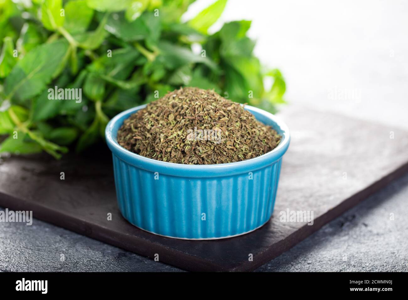 Dried peppermint in a white bowl and a bunch of fresh mint, on stone ...
