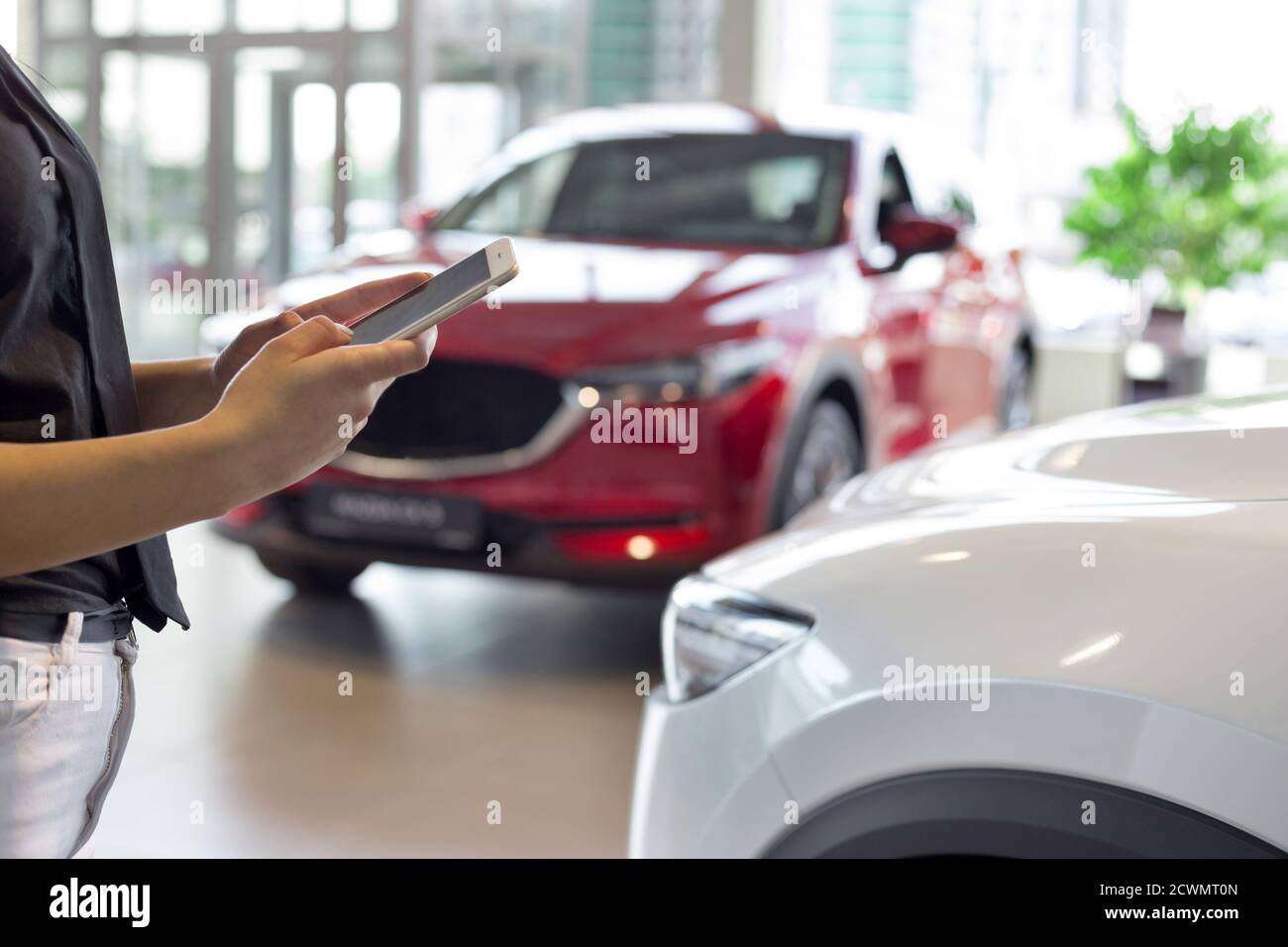 Woman dealer using mobile smart phone at dealer showroom. Modern ...
