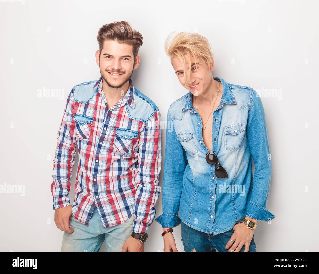 happy smiling young casual men standing together against studio ...