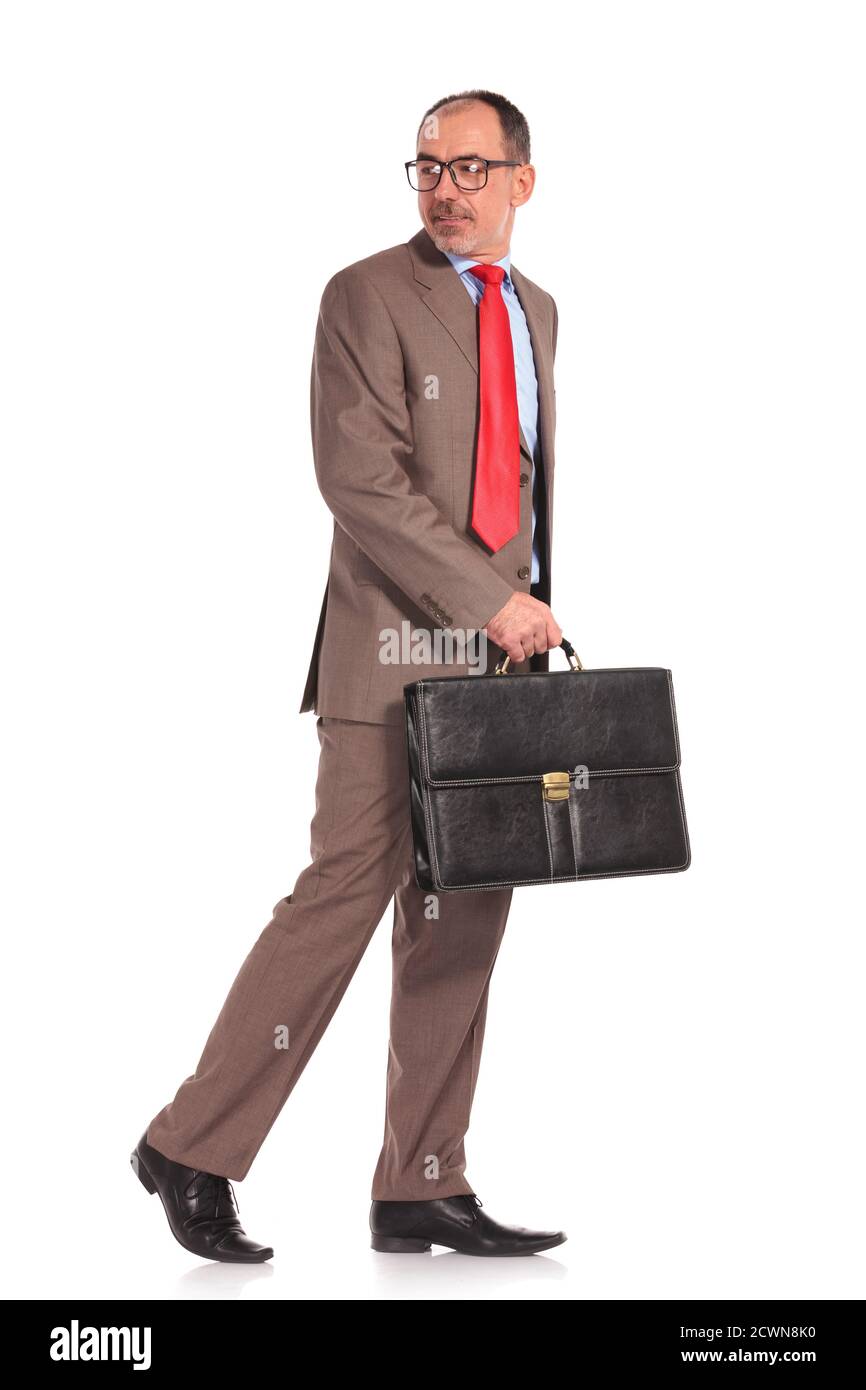 side view of a walking old businessman looking back over his shoulder ...