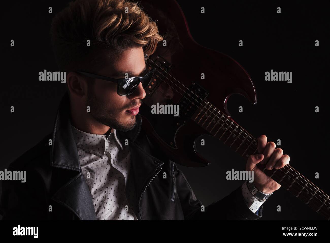 closeup portrait of a young guitarist holding his electric guitar next ...